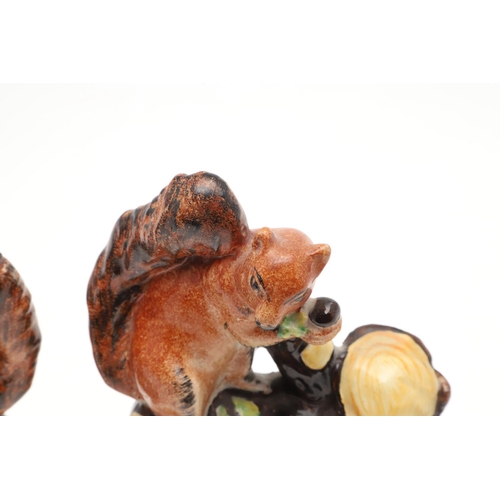 PAIR OF STAFFORDSHIRE RED SQUIRRELS. A pair of pottery figures of Red Squirrels, each perched on a t