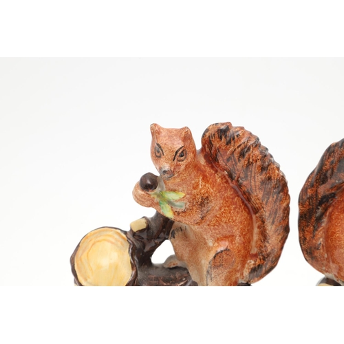 PAIR OF STAFFORDSHIRE RED SQUIRRELS. A pair of pottery figures of Red Squirrels, each perched on a t
