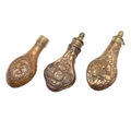 A COLLECTION OF THREE HIGHLY DECORATED COPPER POWDER FLASKS. A copper ...
