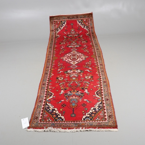 A HAMADAN RUNNER. The raspberry field with an ivory central medallion ...