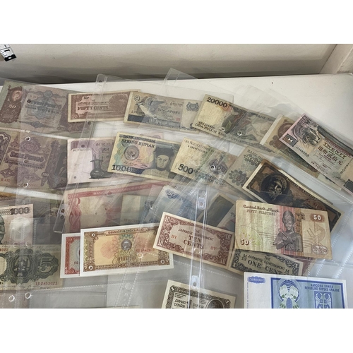A folder full of world bank notes with loose bank notes