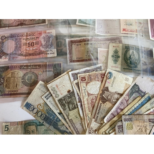 A folder full of world bank notes with loose bank notes