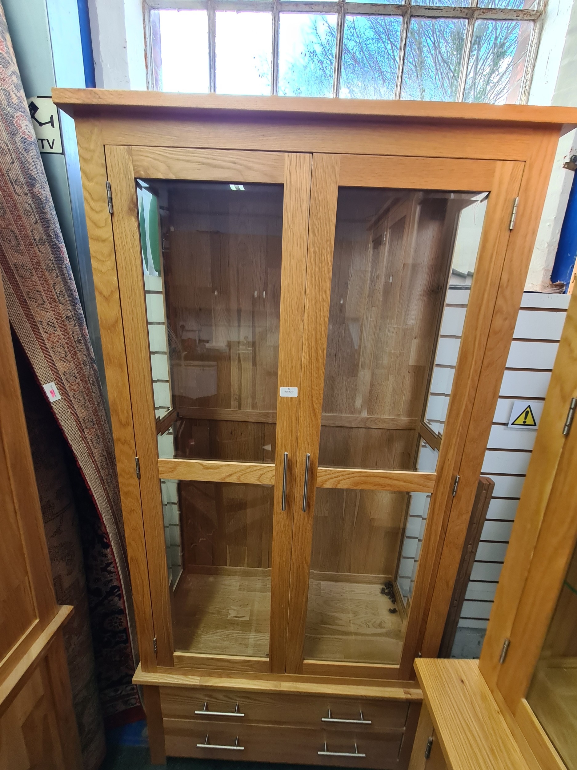 A modern oak two door display cabinet with two lower drawers, 91cms