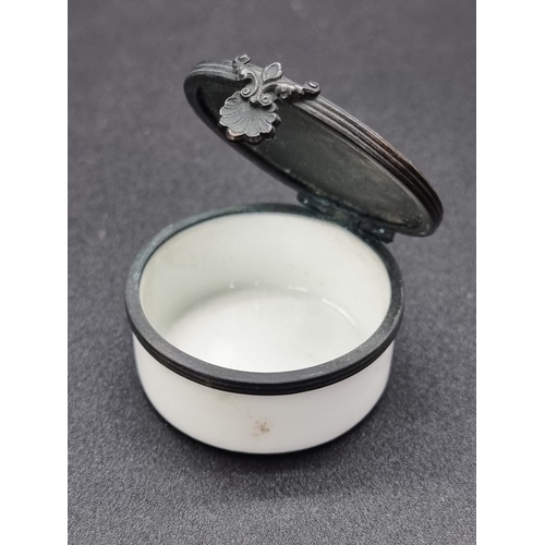 An opaque glass and patinated metal 'Napoleon' pill box, 4.8cm diameter.