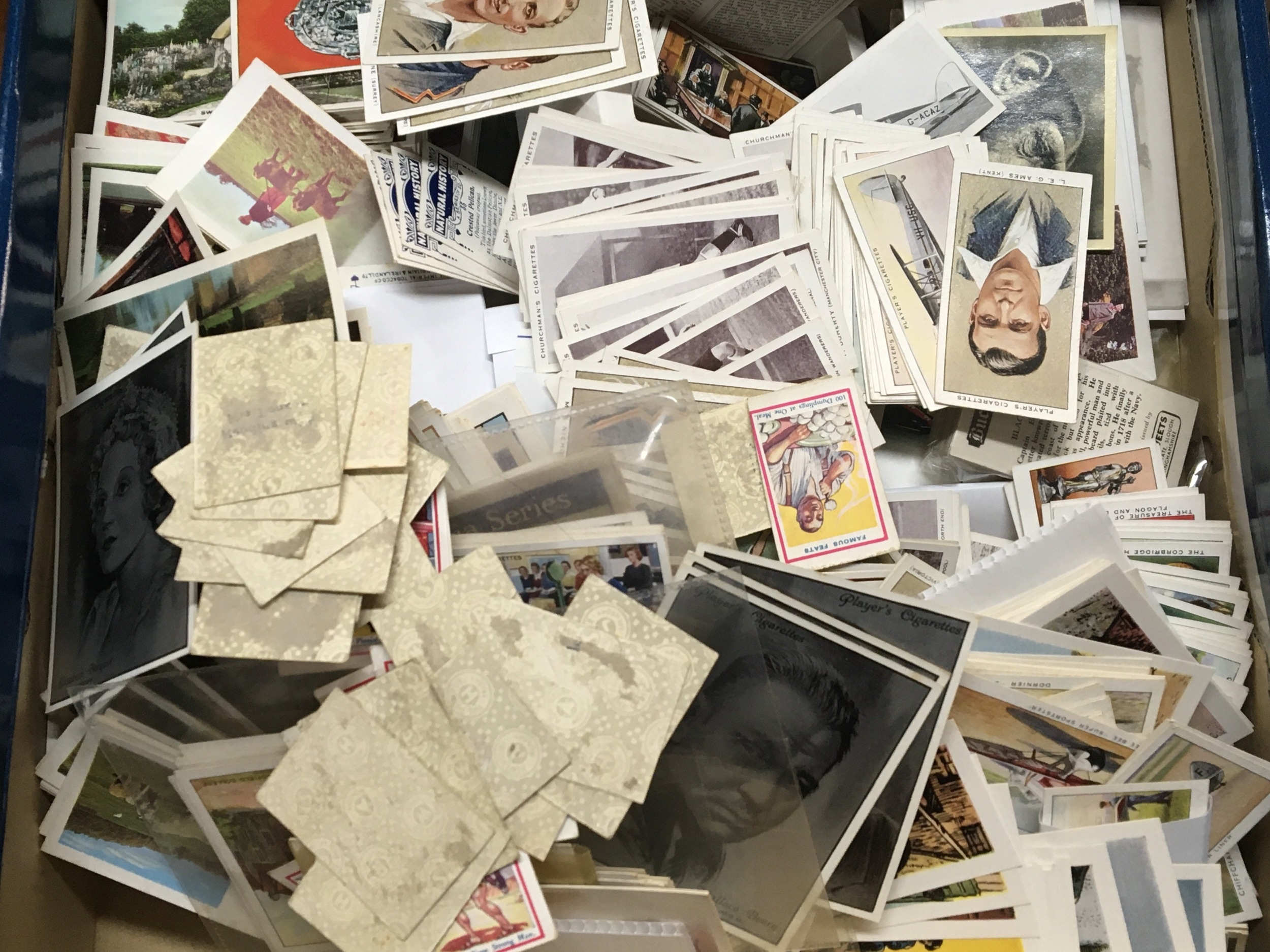 A box containing a collection of loose vintage cigarette cards and ...