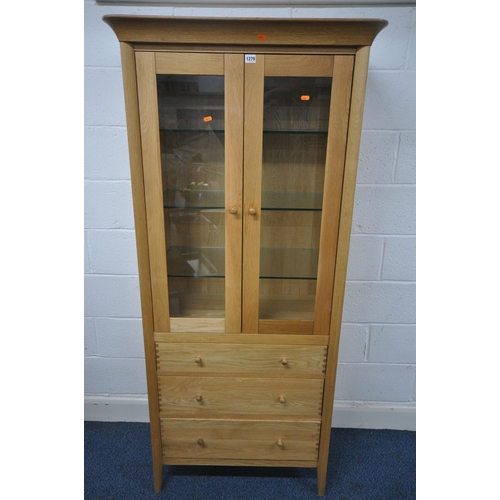 A JOHN LEWIS SOLID OAK BOOKCASE, the two glazed doors enclosing three ...
