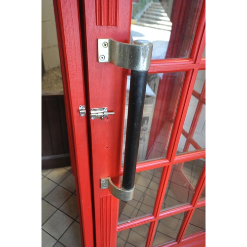 A BESPOKE RED PAINTED PINE TELEPHONE BOX, with a single swing door ...