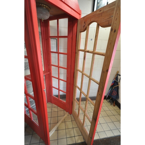 A BESPOKE RED PAINTED PINE TELEPHONE BOX, with a single swing door ...