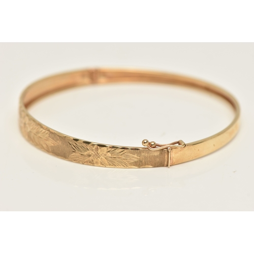 A 9CT GOLD ETCHED PATTERN HINGED BANGLE, fitted with a figure of eight ...