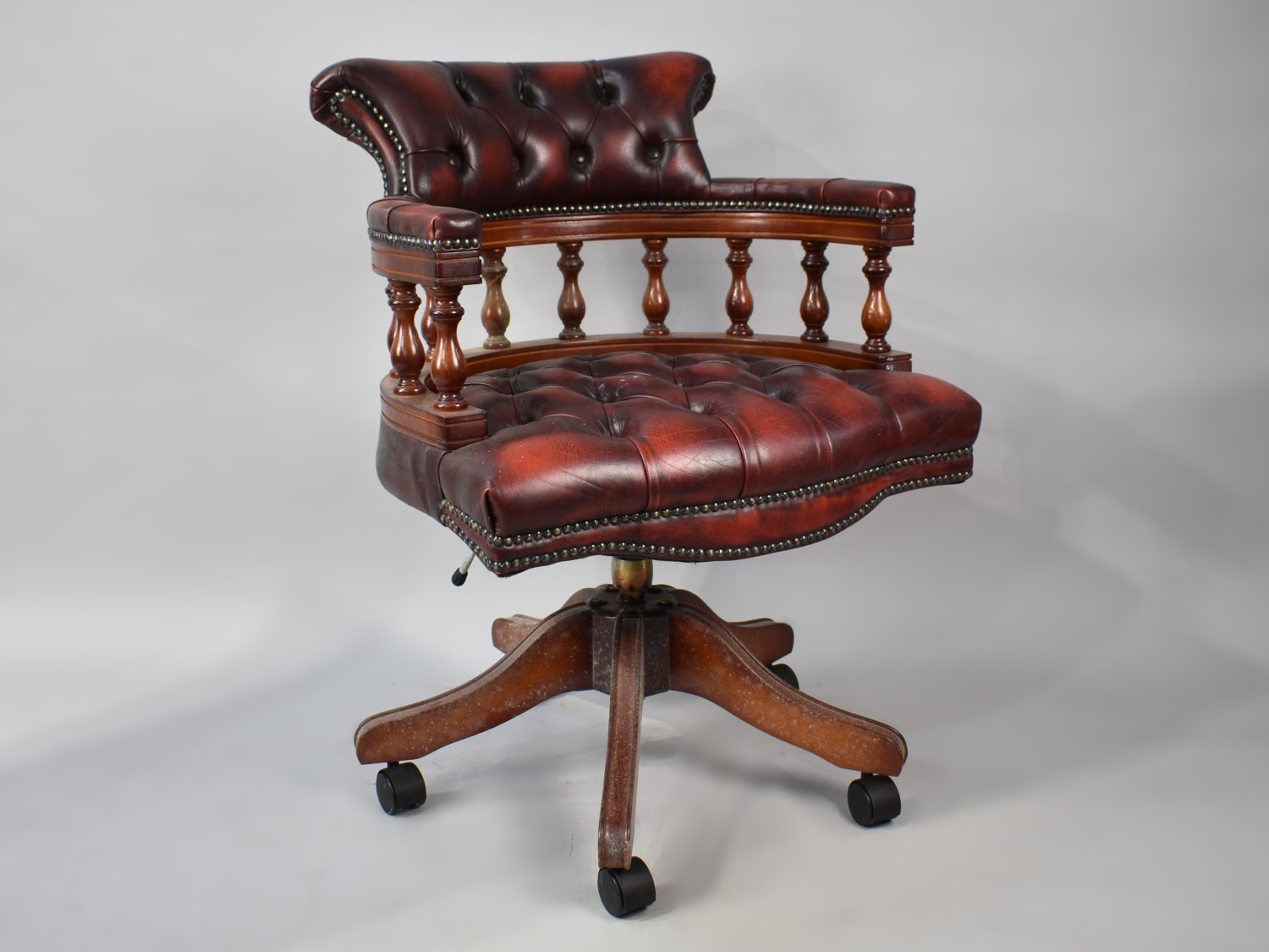 A Buttoned Red Leather Effected Swivel Office Armchair with Brass ...