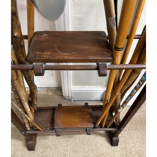 A wooden umbrella stick stand containing a selection of wooden walking ...