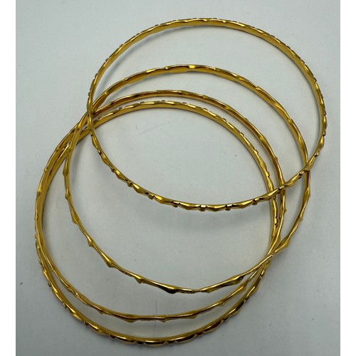 Four yellow bangles. Test as approximately 21 carat gold. Total weight ...