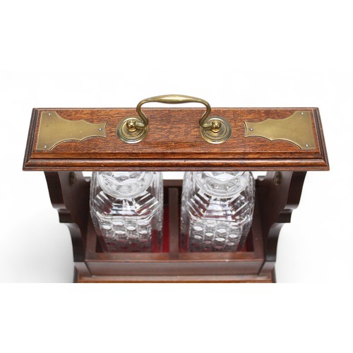 A 20th Century stained mahogany tantalus, with mounted brass fittings ...