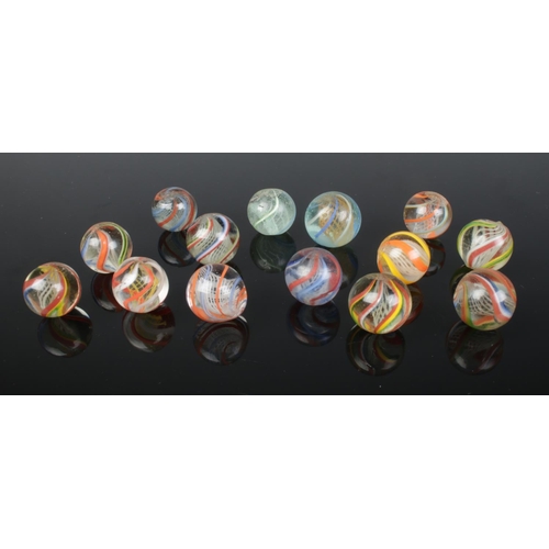 Fourteen antique glass latticino marbles with air twist decoration.