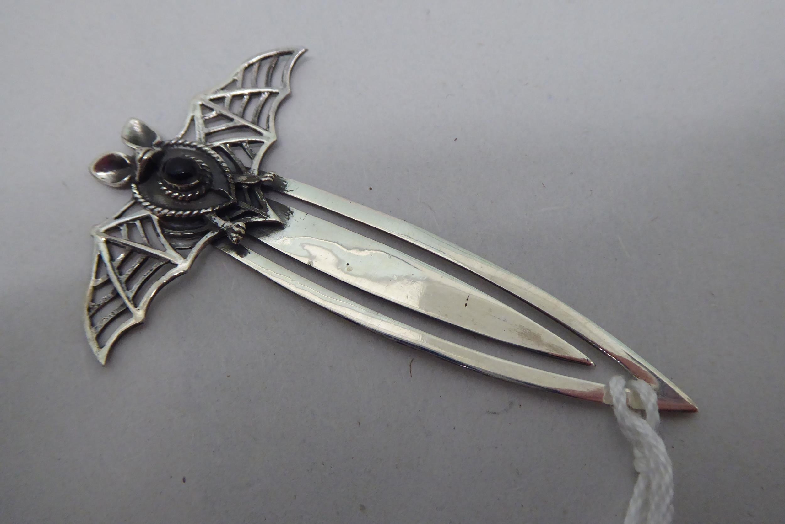 A silver coloured metal page marker with a bat finial stamped 925