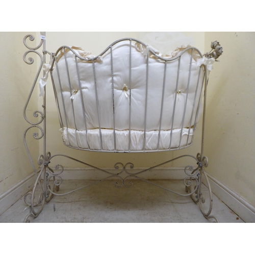 A mid 20thC overpainted cast metal hanging bassinet, decorated with ...