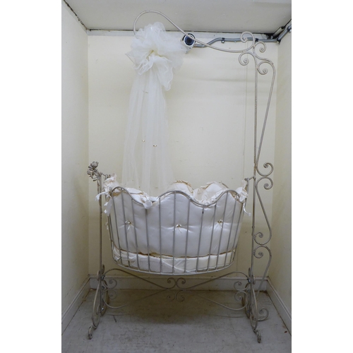 A mid 20thC overpainted cast metal hanging bassinet, decorated with ...