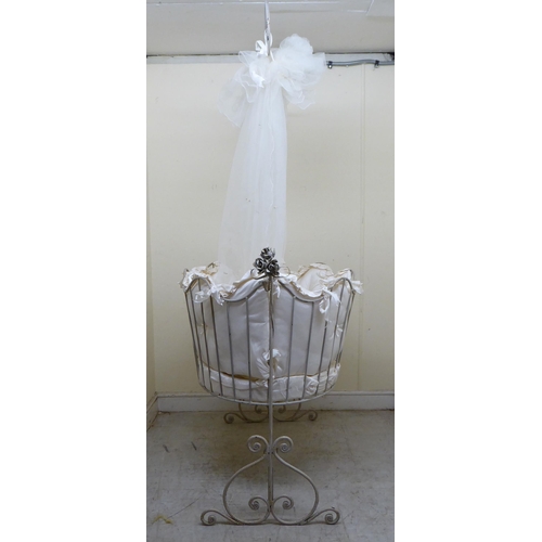 A mid 20thC overpainted cast metal hanging bassinet, decorated with ...