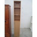 A modern slim storage tower with open shelves and lower cupboard