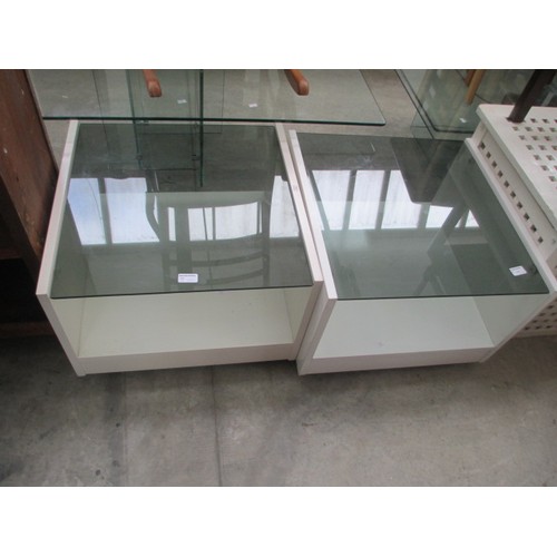 A pair of modern glass topped tables on casters