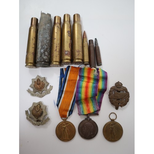 A collection of spent ammunition shells, two Cheshire Regiment Cap ...