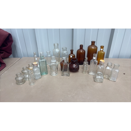 Collection of assorted clear and amber glass bottles, including ...