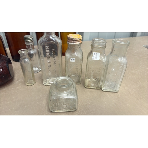 Collection of assorted clear and amber glass bottles, including ...