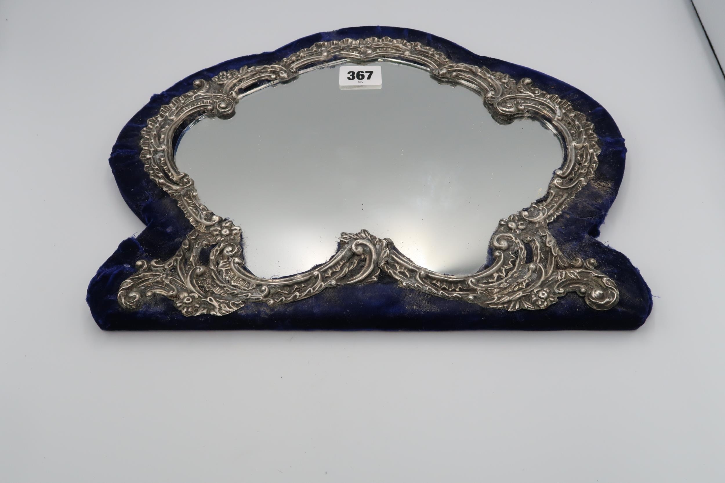 A Silver H.M. mirror With scrolling foliate surround.