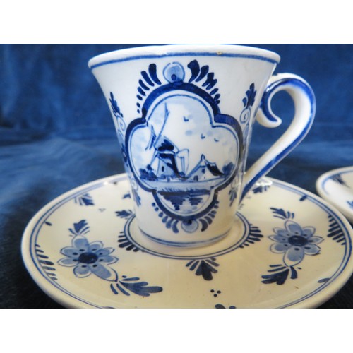 Two Delft ware cups and saucers with hand-painted decoration.