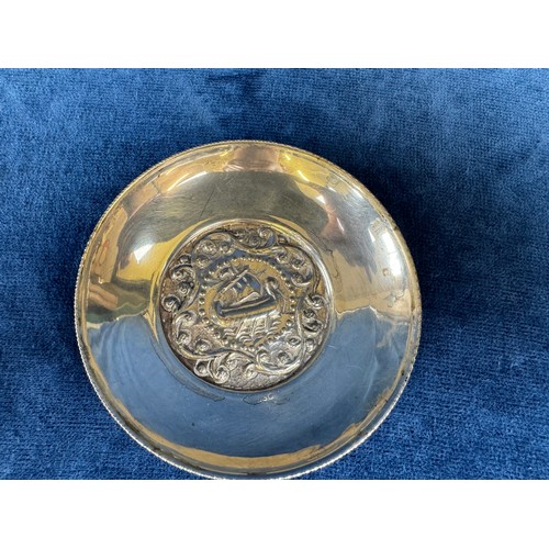 A small circular dish with central image of a boat with floral surround ...