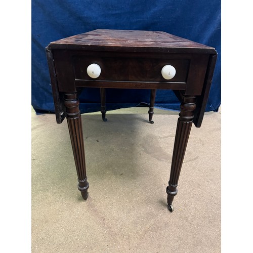 An antique mahogany drop leaf table on four reeded legs and castors ...