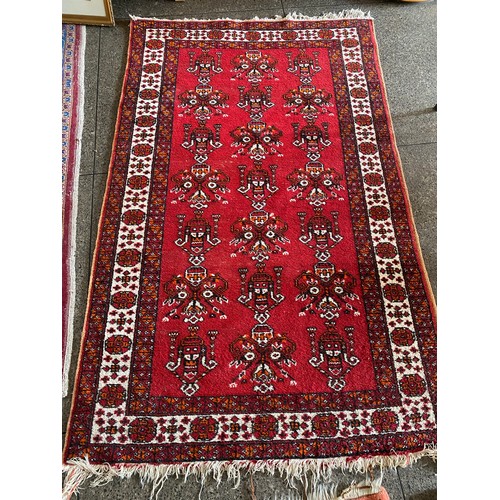 An Eastern rug, red field with twenty one stylised repeating medallions ...