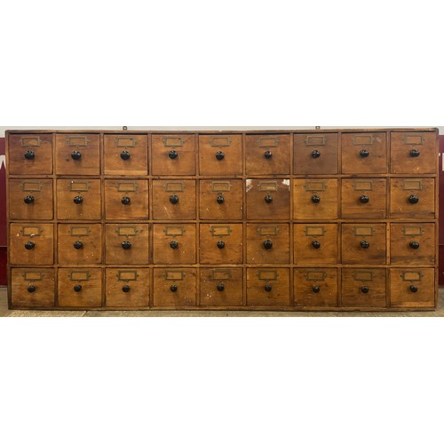 An early 20th Century pine wall hanging bank of thirty-six index drawers