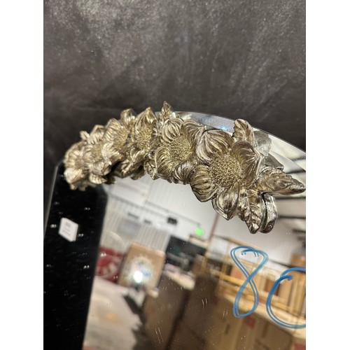 A bevelled edge arched mirror with floral design top and bottom
