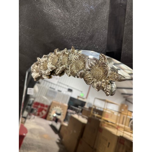 A bevelled edge arched mirror with floral design top and bottom