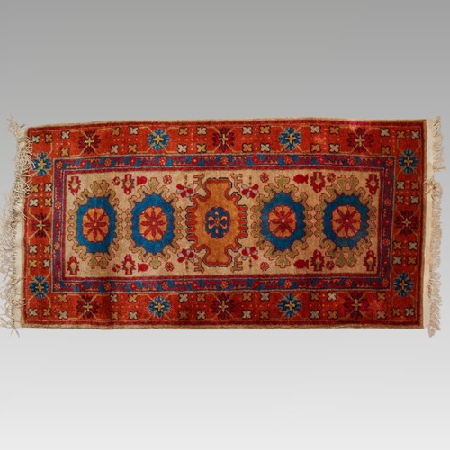 A 20th century Turkish woollen rug, red, blue and beige ground with ...