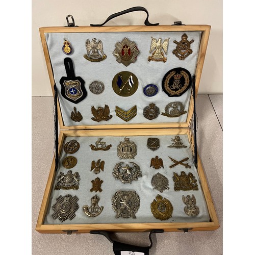 A collection of 34 military cap badges & insignia displayed in a wooden ...