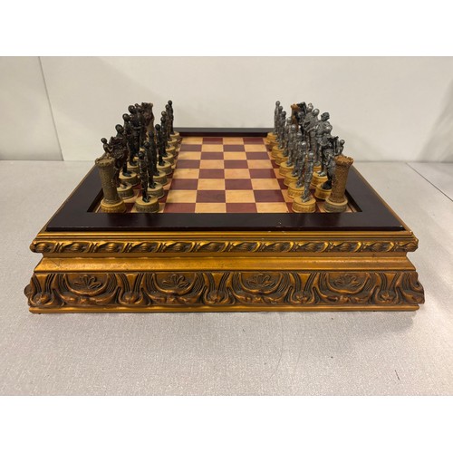 Chess set with medieval figures ornate scroll work board base.
