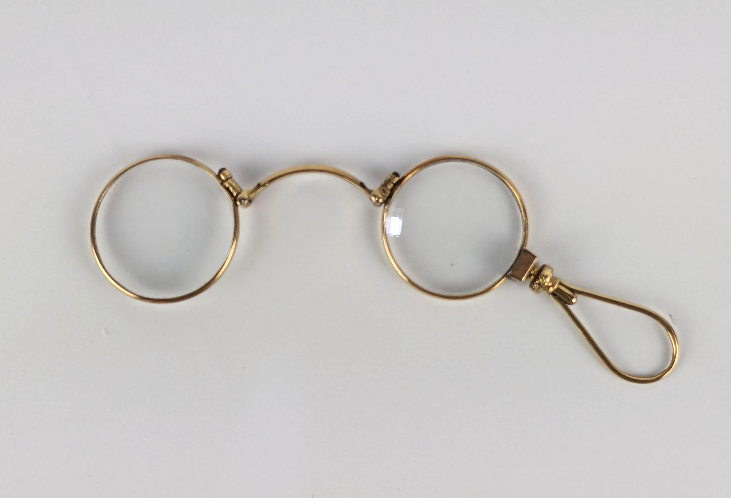 A pair of gold mounted folding lorgnettes with a loop form handle ...