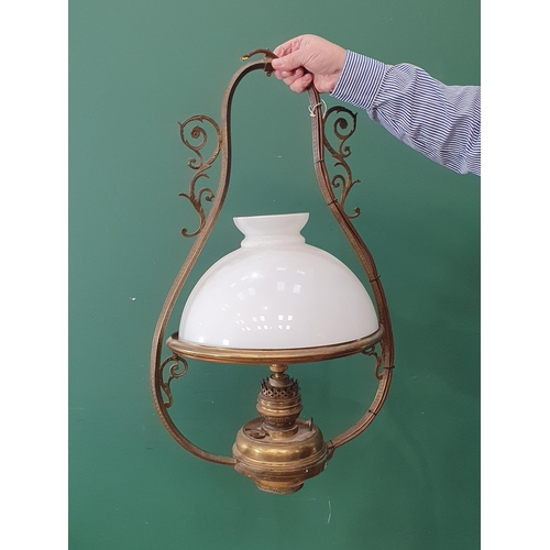 A brass hanging Paraffin Lamp with scroll decoration and an opaque ...
