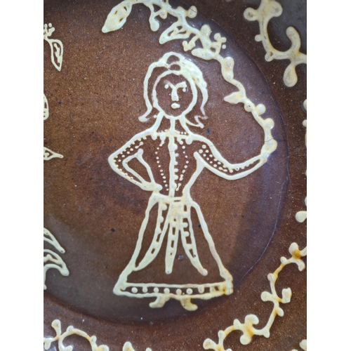 A slipware Charger decorated with Figure and Flowers and bearing the ...