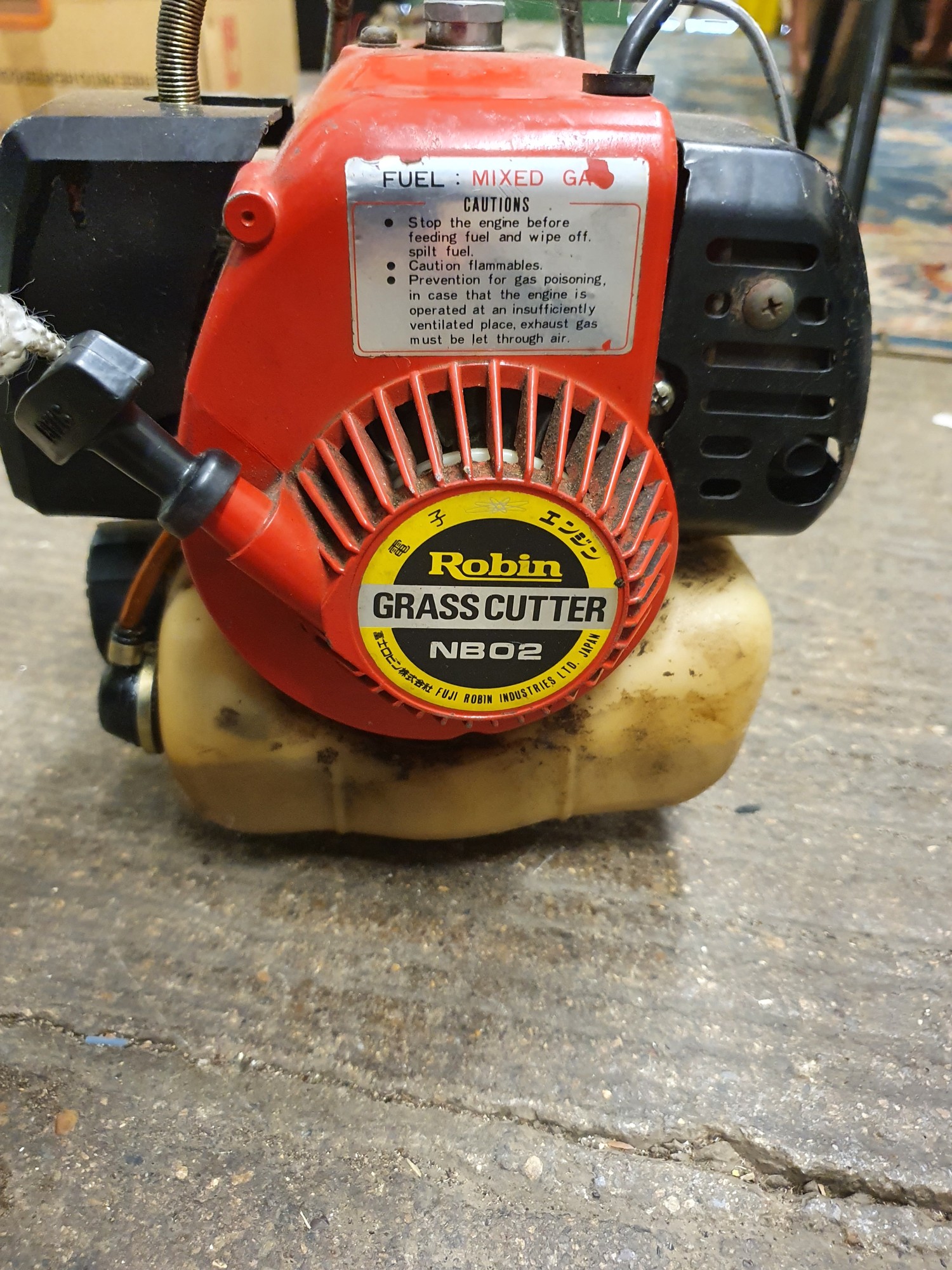 A Robin NB02 petrol strimmer, with shoulder strap and instruction manual.