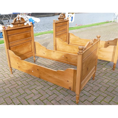 A pair of modern pine single bedsteads, together with a black tubular metal single bedstead with fit