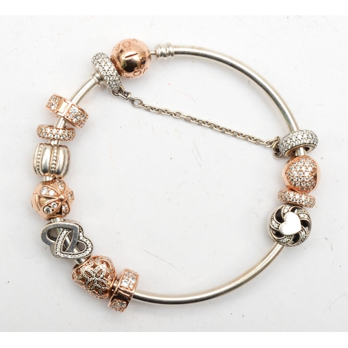Pandora, a silver charm bangle with charms to include rose gold plated ...