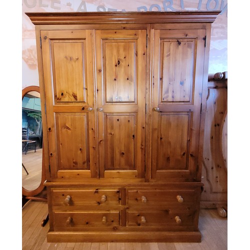 A modern pine triple wardrobe, three panelled doors over four long ...