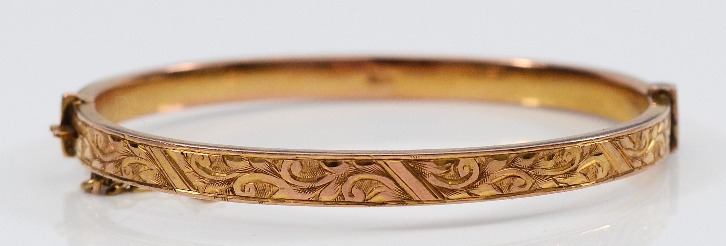 A 9ct rose gold children's hinged bangle, Birmingham 1910, with floral ...