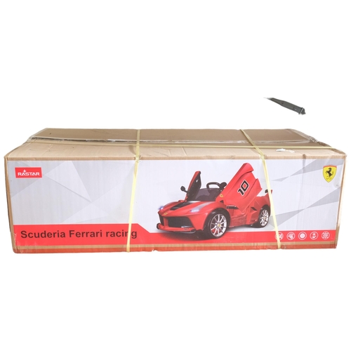 A child's battery operated ride-on Scuderia Ferrari racing car in red ...