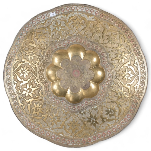 A large Antique Indian brass tiffin table top of shaped form, heavily ...