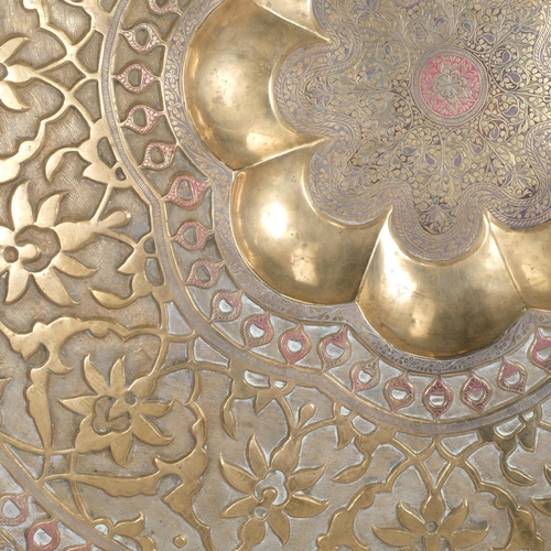 A large Antique Indian brass tiffin table top of shaped form, heavily ...