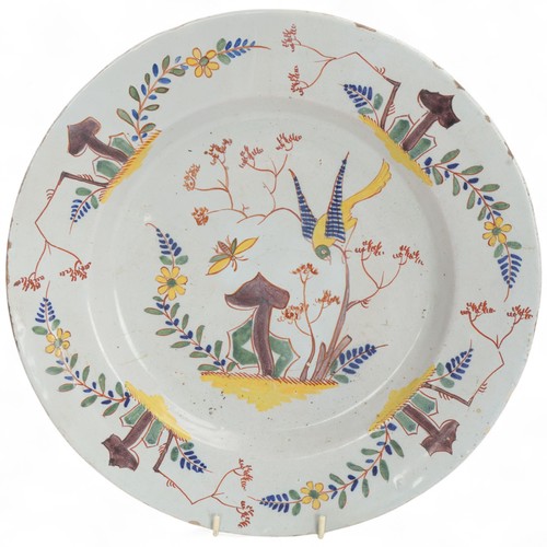 A large 18th century English Delft charger, decorated with exotic bird ...
